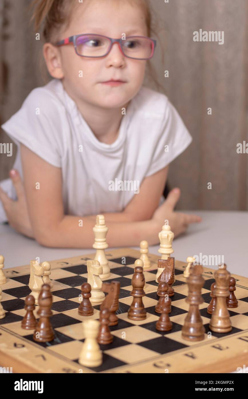 Cute little girl thinking chess at home Stock Photo - Alamy