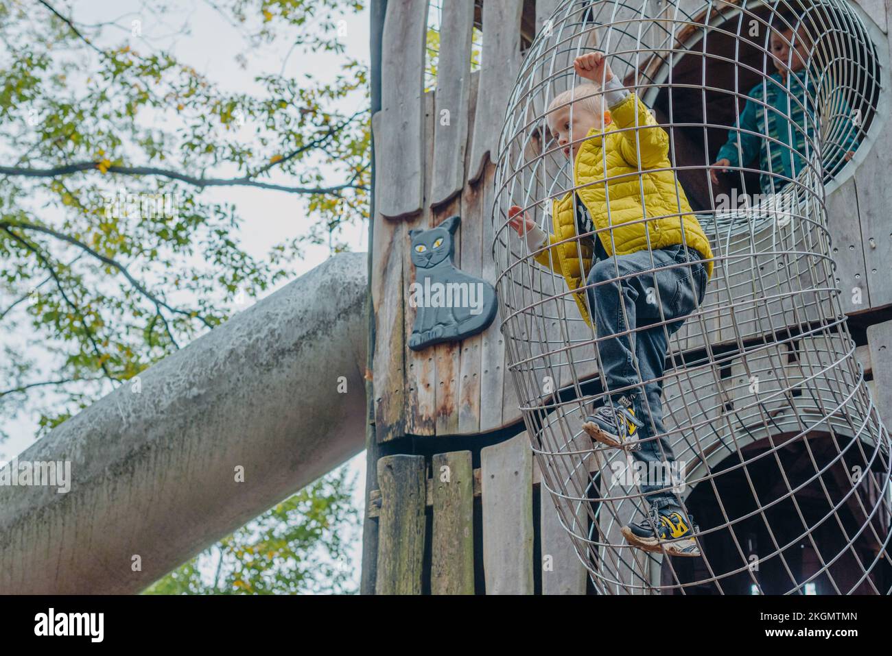 A child climbs up an alpine grid in a park on a playground on a hot ...