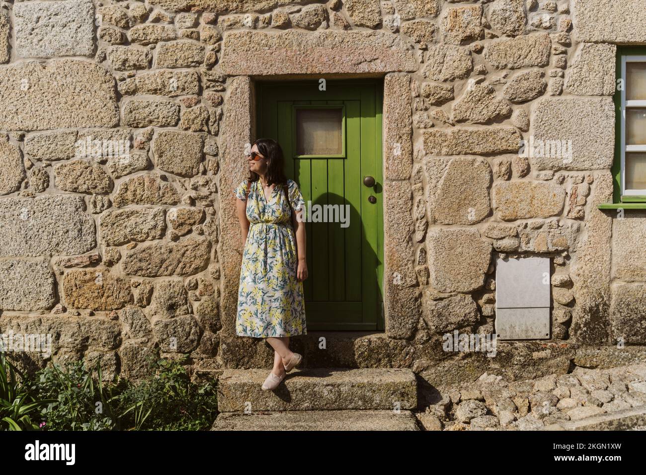 A female standing near a green door of an old house in Castelo Novo ...