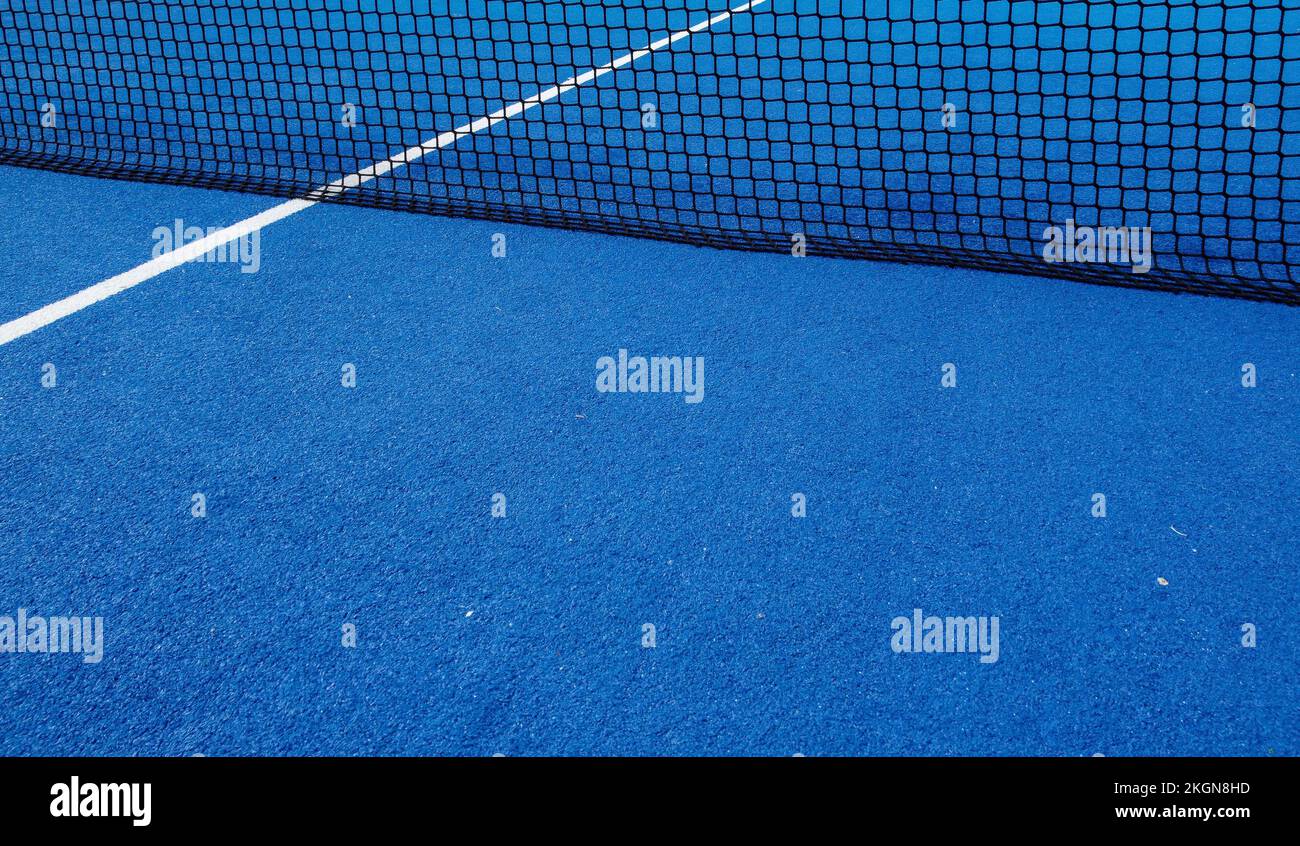 A closeup of a net and the center line of a blue paddle tennis court ...