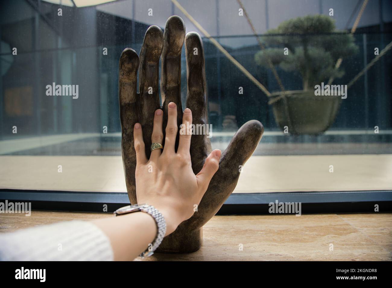 A closeup shot of girls hand on wooden humans hand sculpture on window ...