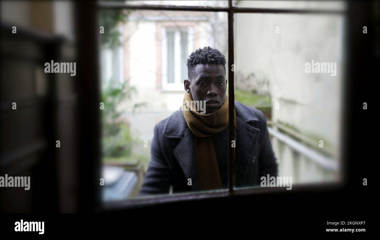 Young black man walking through corridor leaving home going outside ...