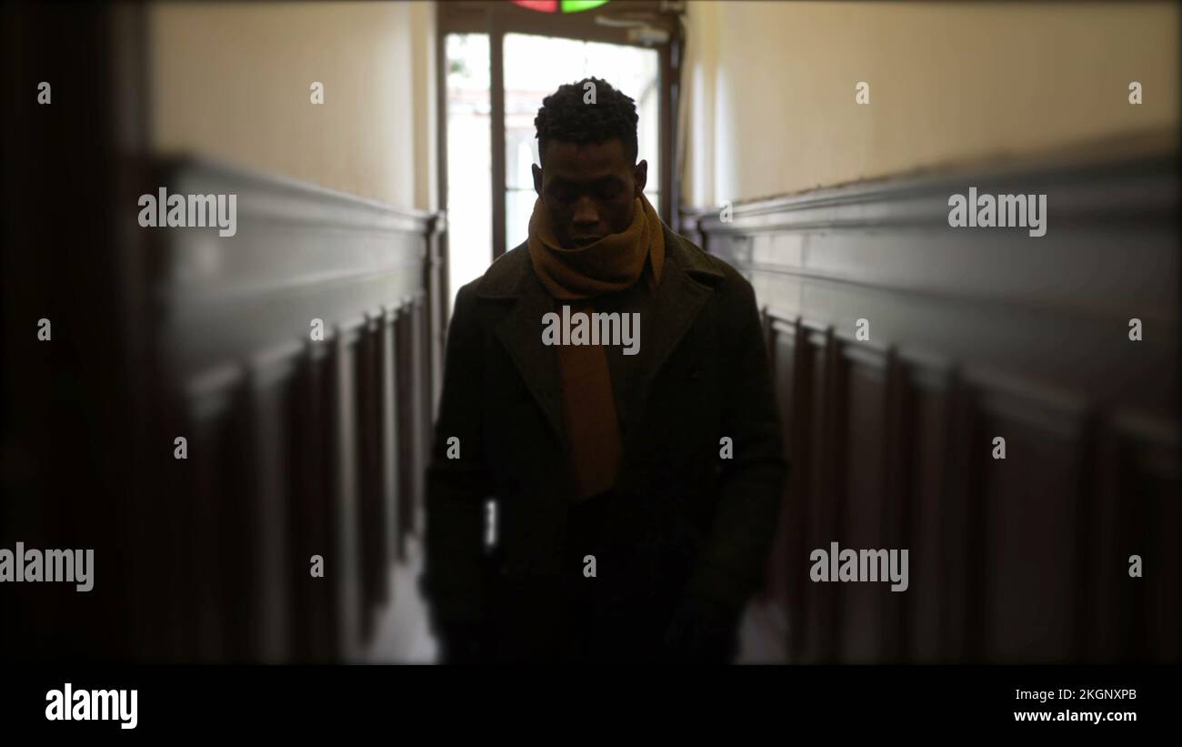 Young black man walking through corridor leaving home going outside ...