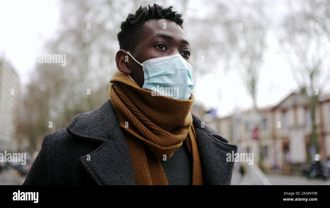 Young black man wearing covid-19 face mask while walking in city ...