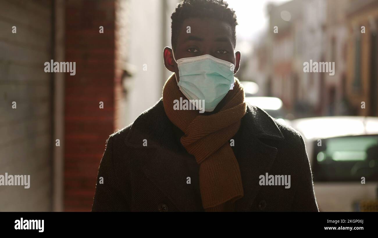 Young black man walking wearing covid surgical face masking. Person ...
