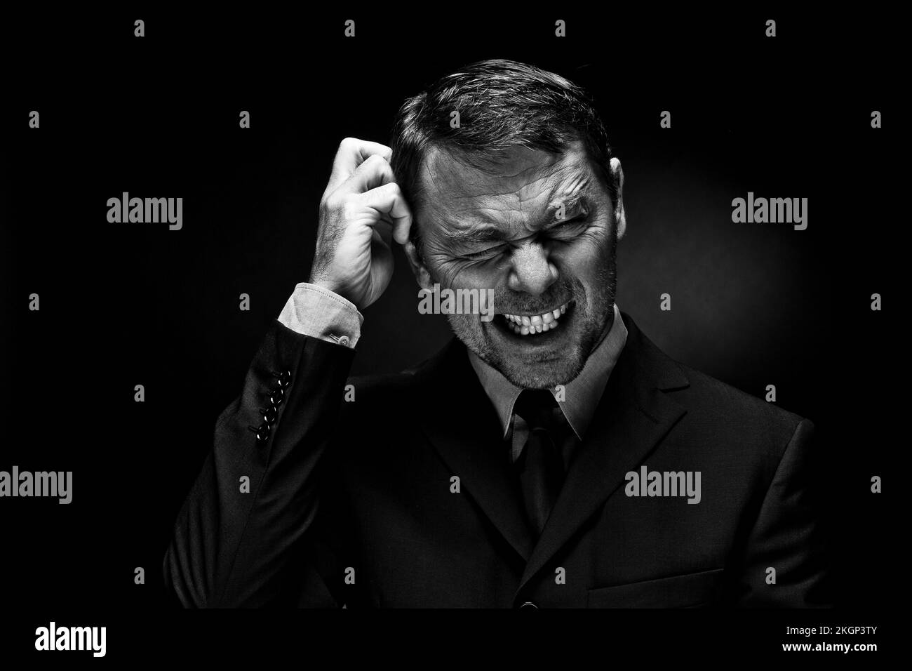 Mature man clenching teeth against black background Stock Photo - Alamy