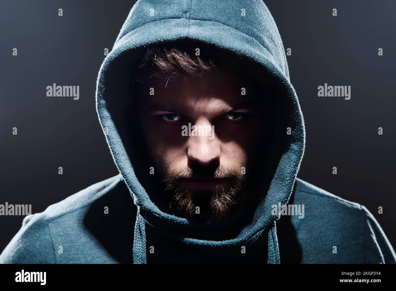 Portrait of man with hooded jacket in front of dark grey background ...