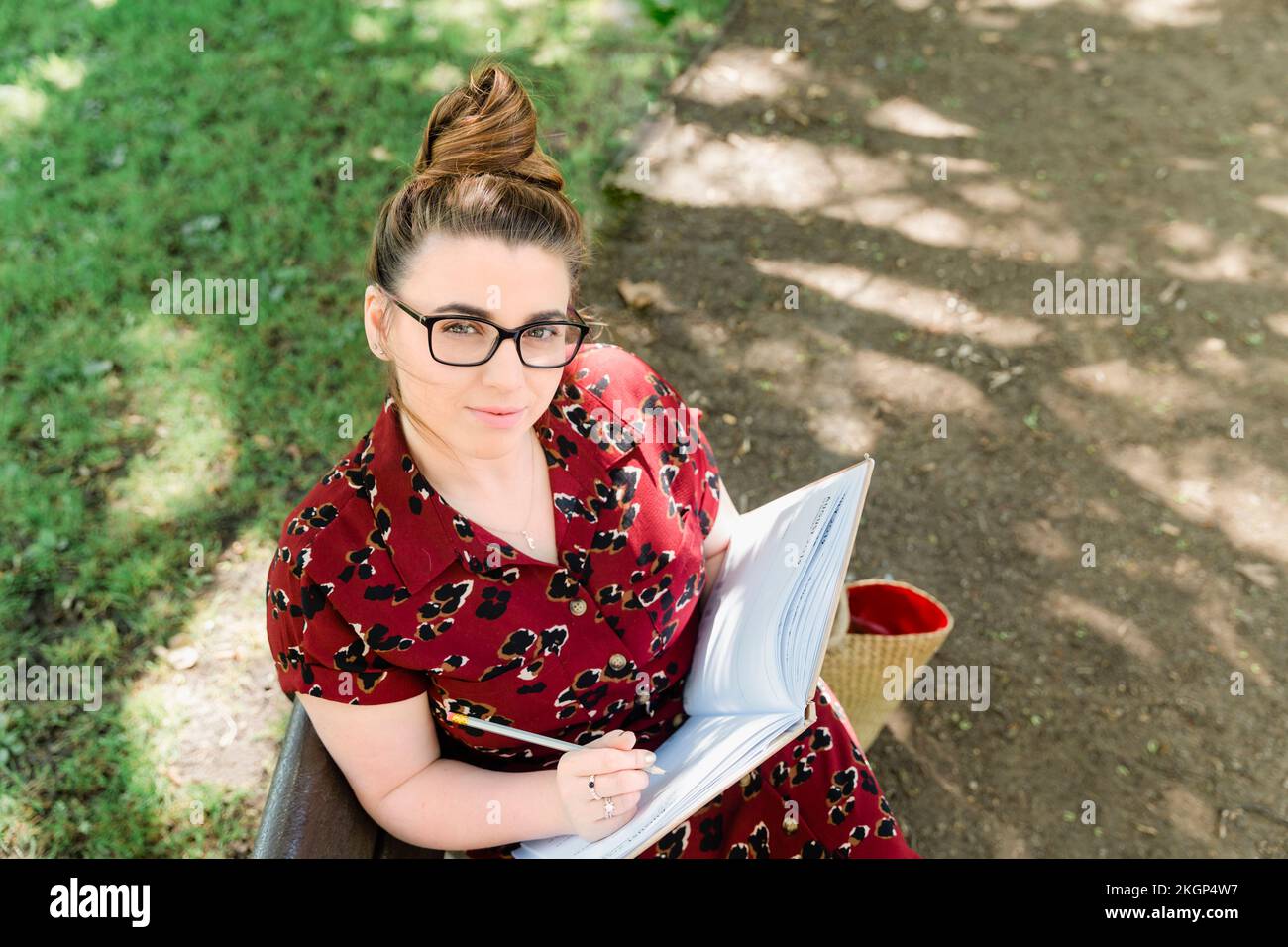 Portrait of woman sitting on bench writing in notebook Stock Photo - Alamy
