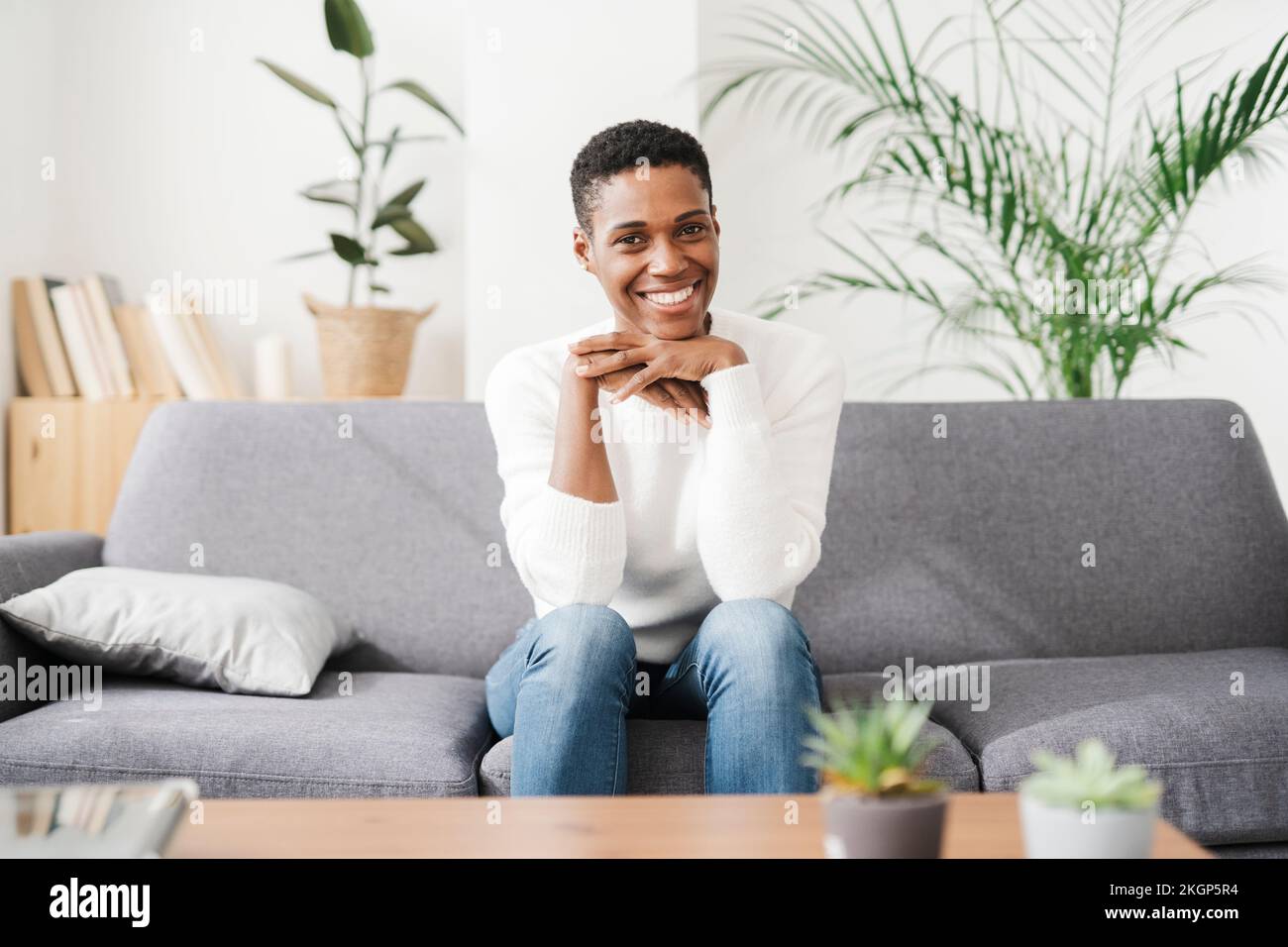 Portrait of smiling woman sitting on couch at home Stock Photo - Alamy