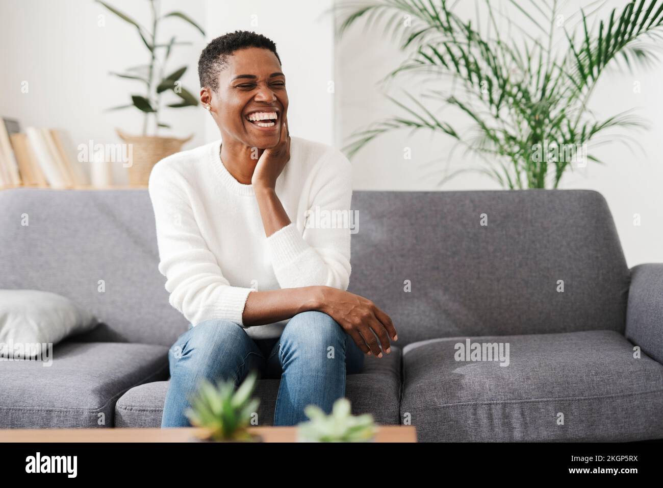 Laughing woman sitting on couch at home Stock Photo - Alamy