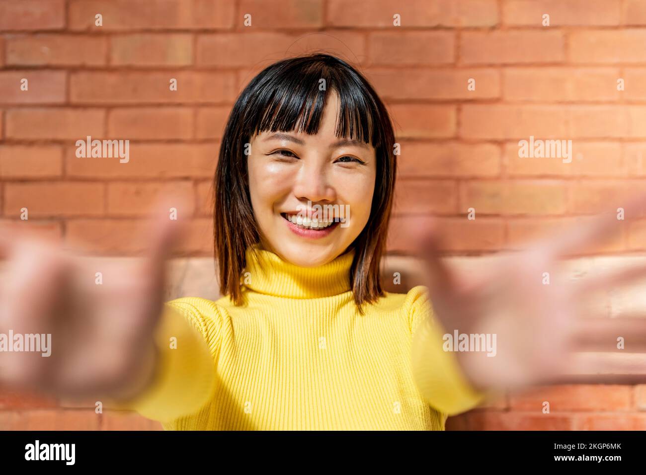 Happy young woman with bangs hair standing in front of wall Stock Photo ...