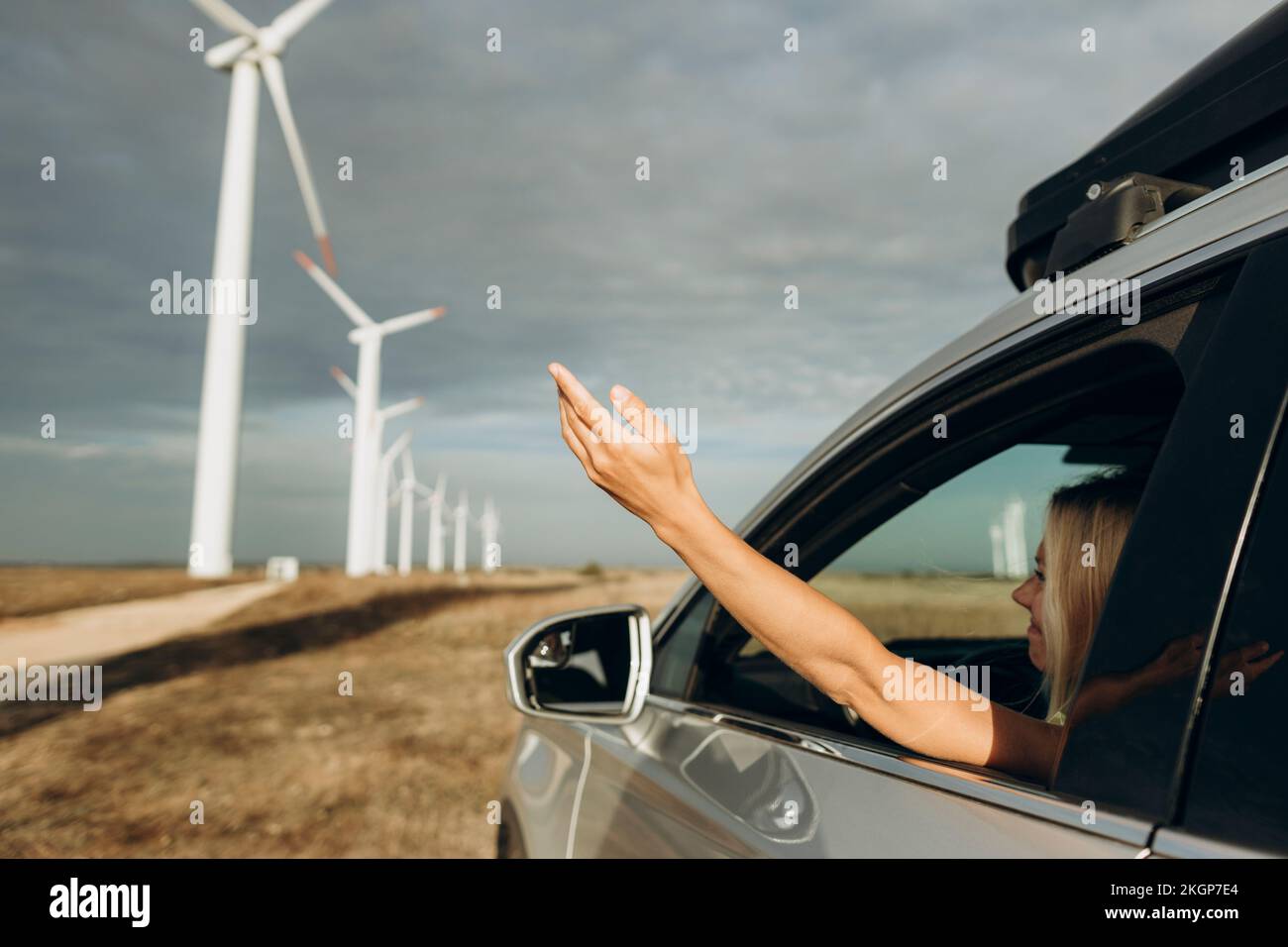Woman sitting with arm raised out of car window at wind park Stock ...