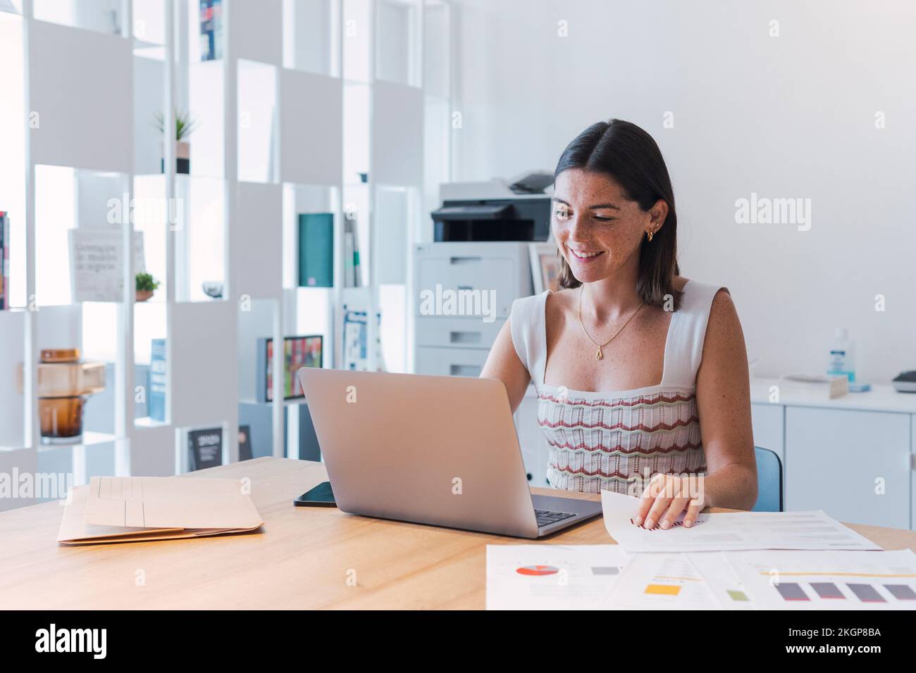 Smiling businesswoman using laptop in office Stock Photo - Alamy