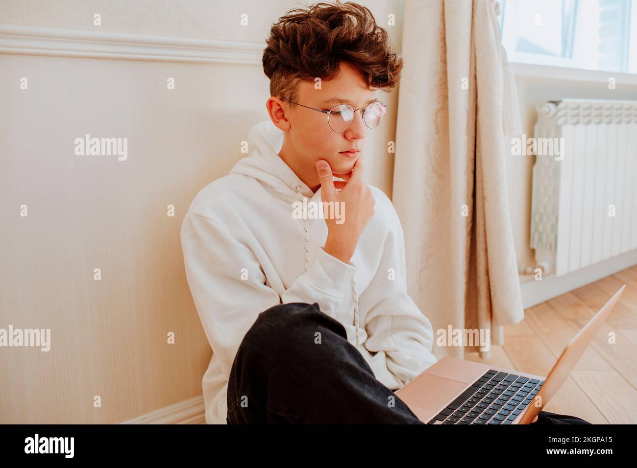 Boy with hands on chin e-learning on laptop Stock Photo - Alamy