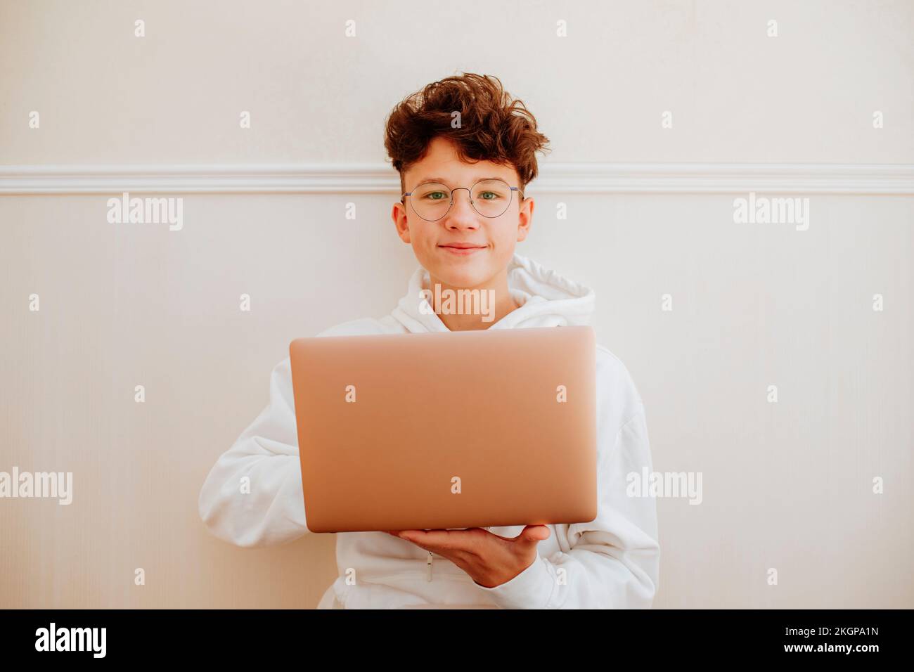 Happy boy sitting with laptop in front of wall Stock Photo - Alamy