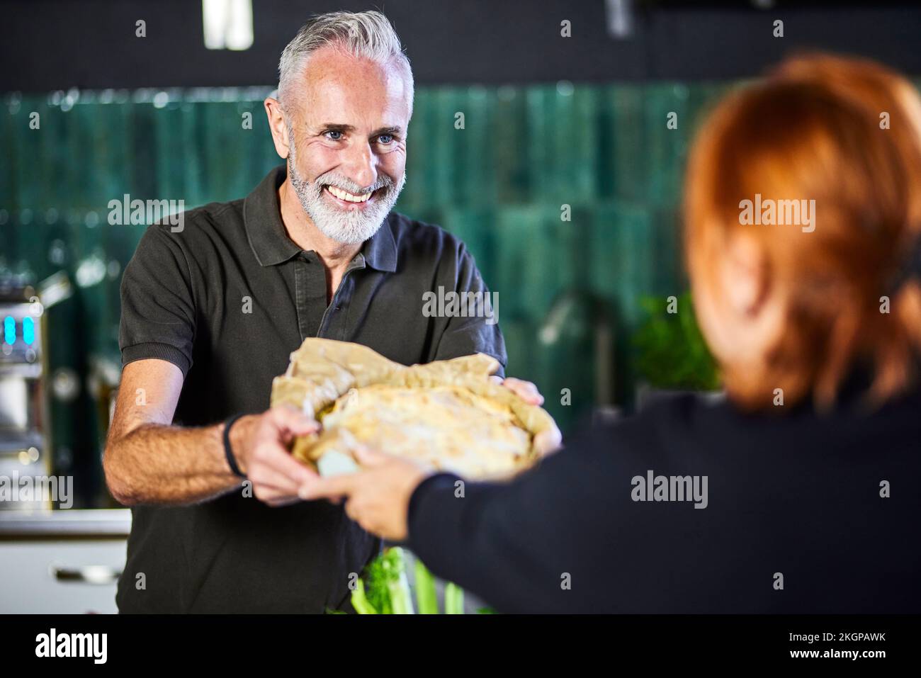 Smiling man handing over savory pie Stock Photo - Alamy