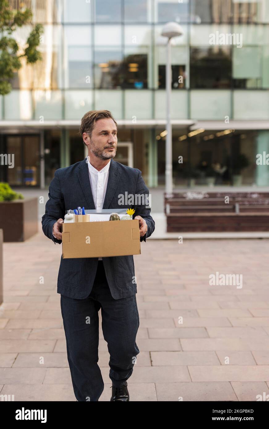 Businessman carrying cardboard box in front of office building Stock ...