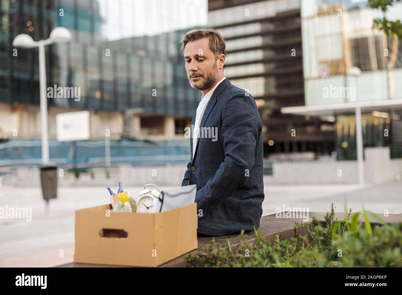 Businessman sitting with cardboard box outside office building Stock ...