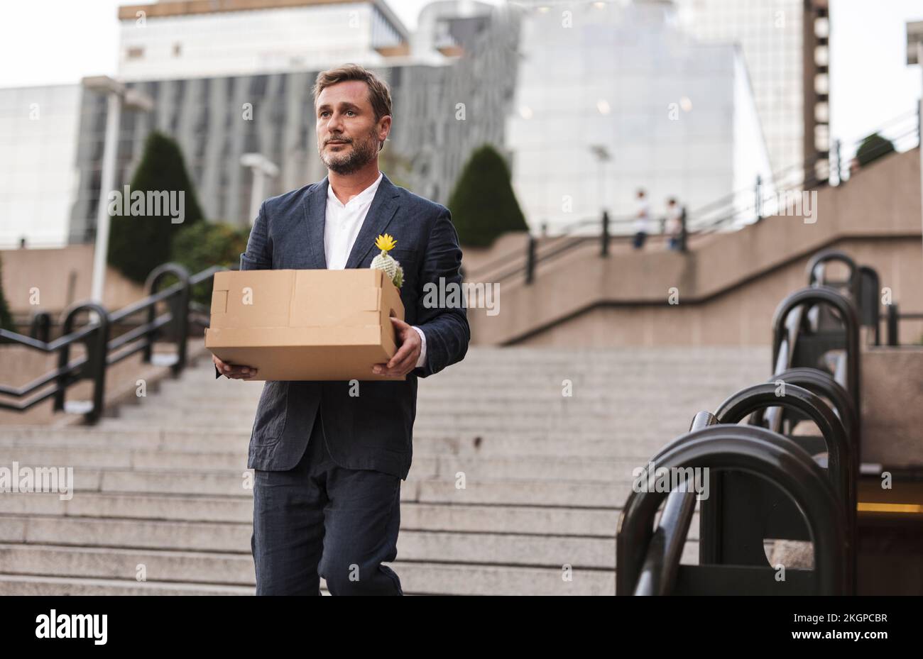 Worried businessman with cardboard box moving down stairs Stock Photo ...