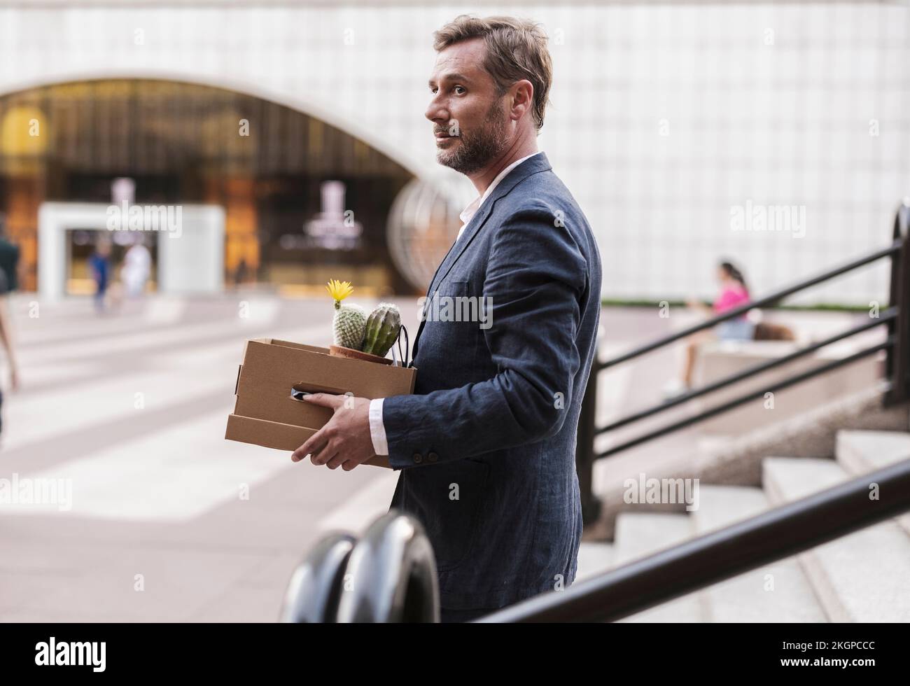 Businessman with cardboard box moving down steps Stock Photo - Alamy