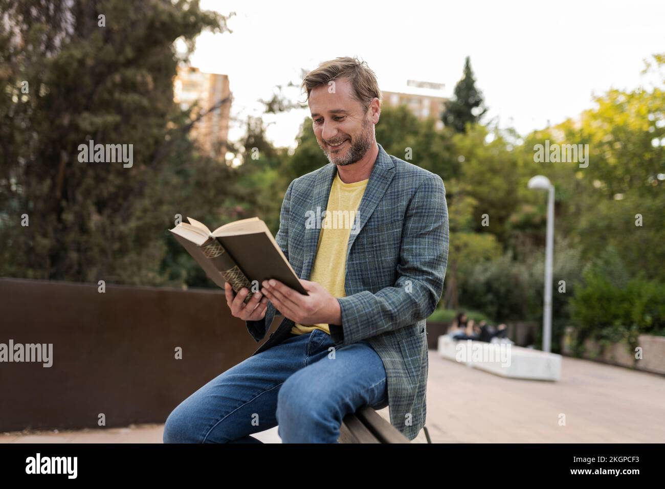 Man sitting bench reading book hi-res stock photography and images - Alamy
