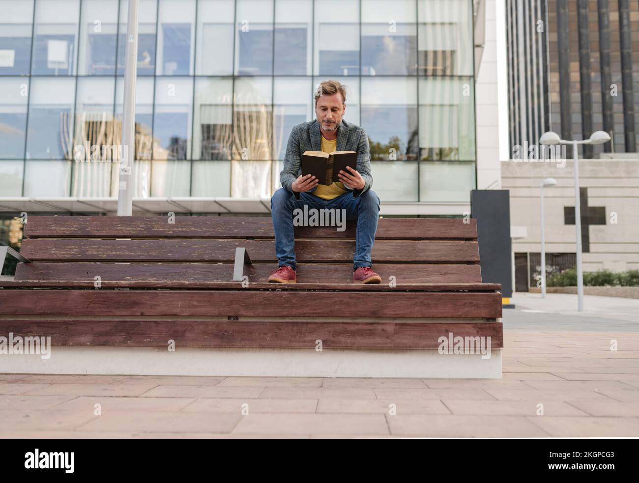 Man sitting bench reading book hi-res stock photography and images - Alamy
