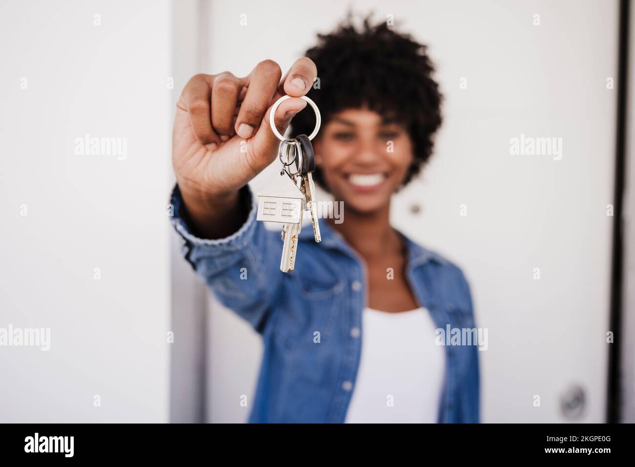 Happy woman showing house keys standing in front of door Stock Photo ...