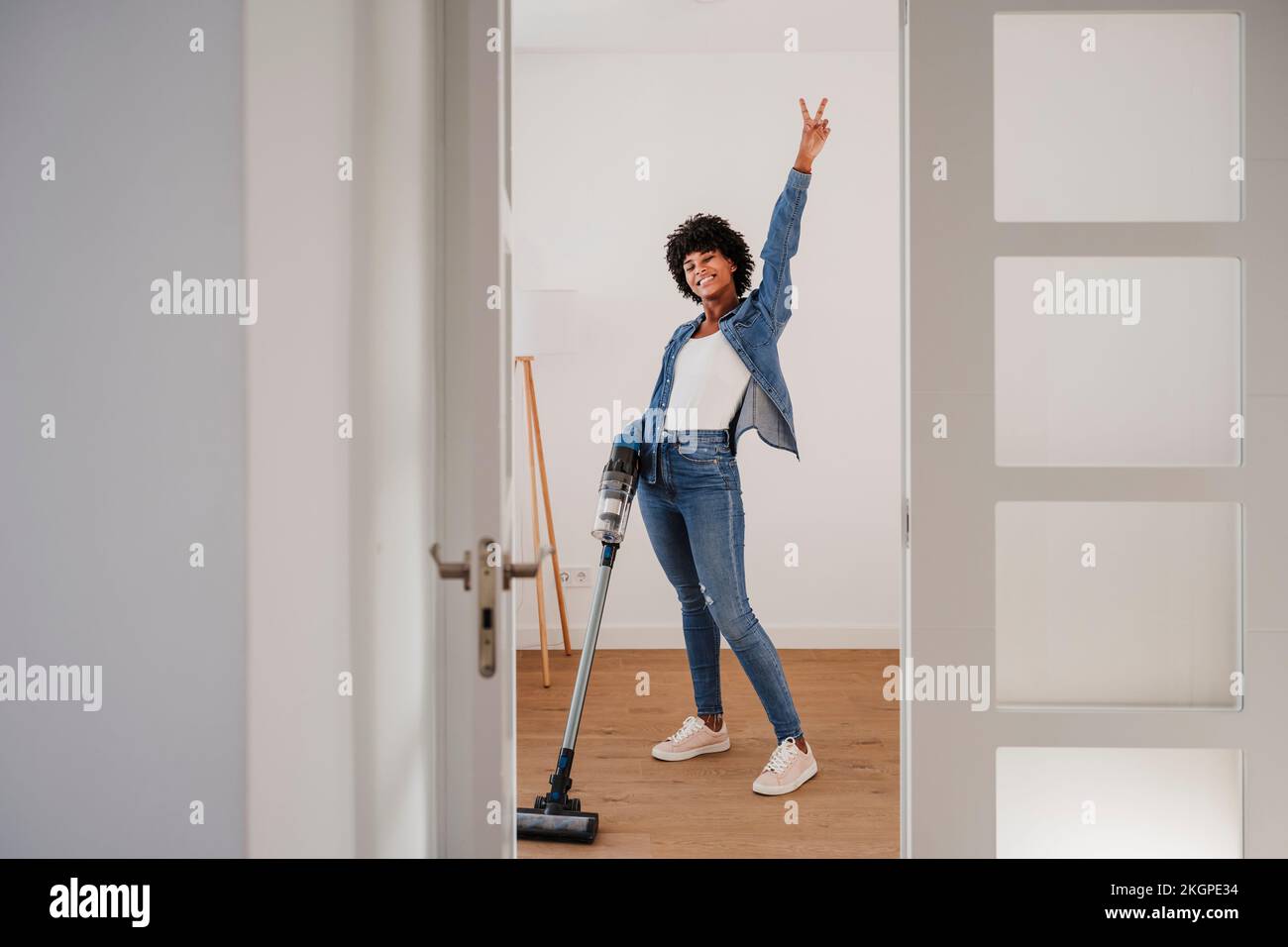 Happy young woman cleaning living room with vacuum cleaner Stock Photo - Alamy