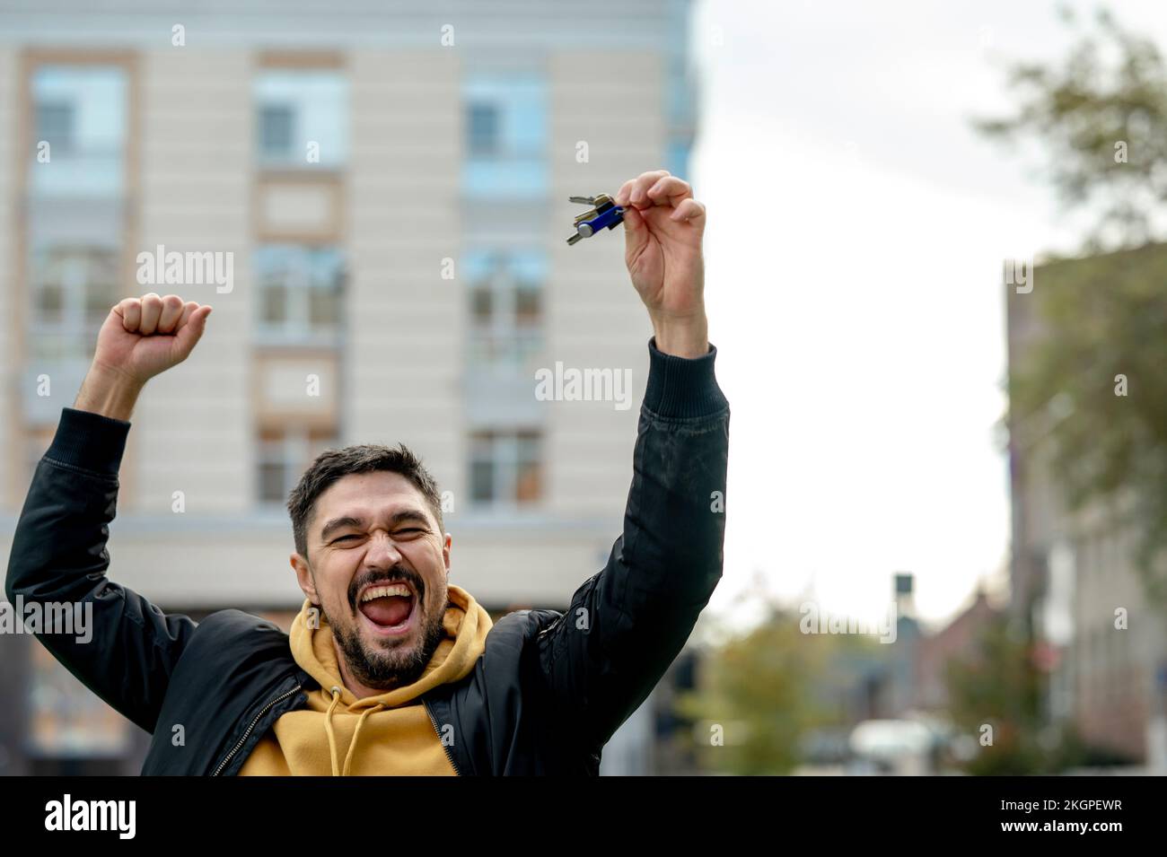 Cheerful man with house keys standing in front of building Stock Photo ...