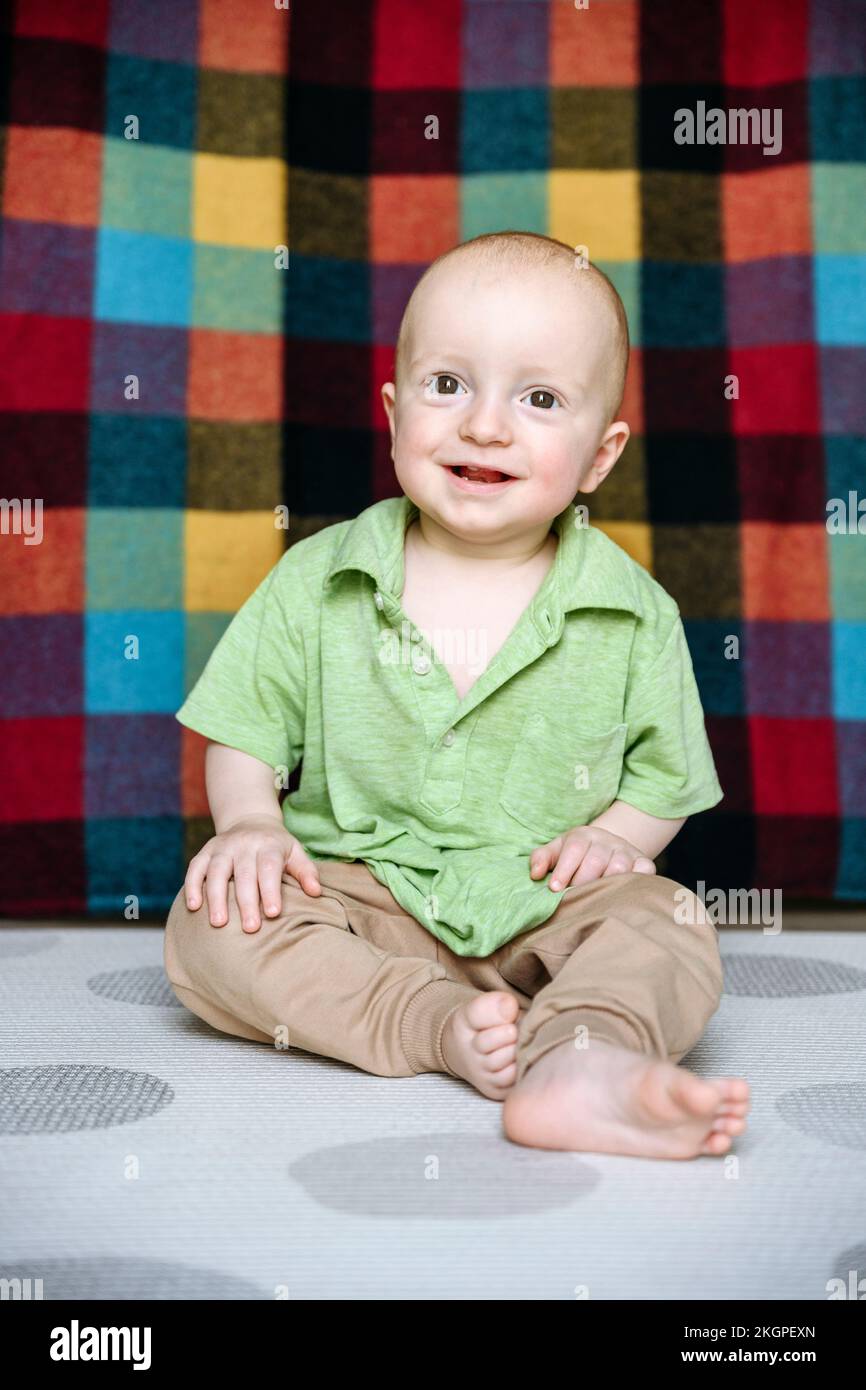 Happy cute boy sitting on carpet Stock Photo - Alamy