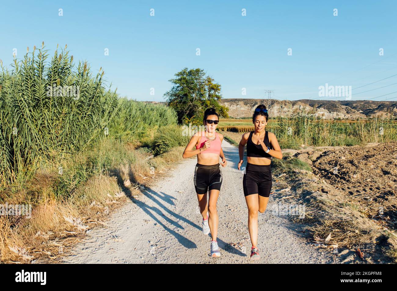 Woman with instructor running on footpath Stock Photo - Alamy