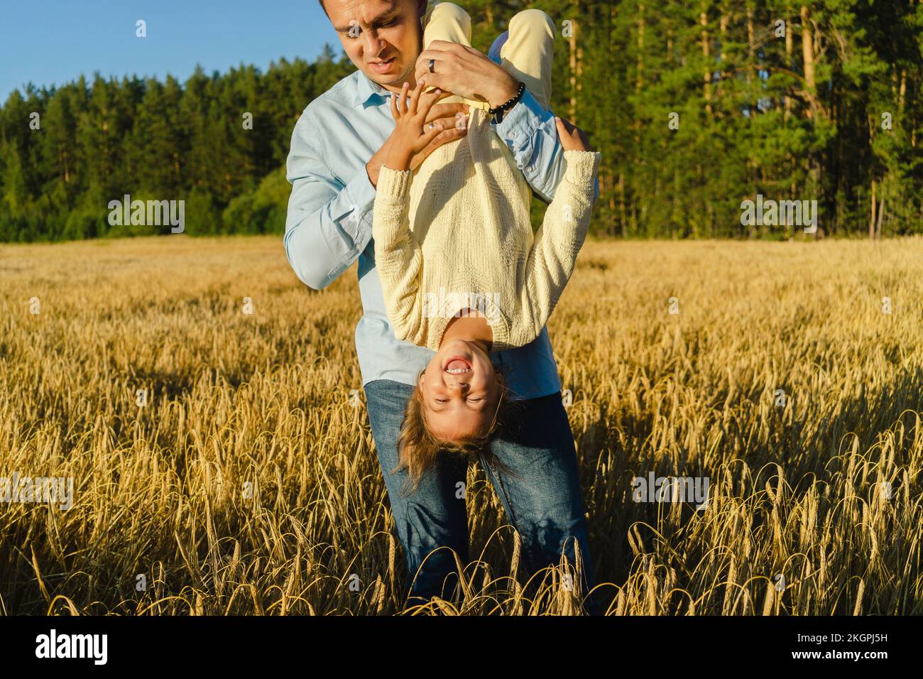 Playful man carrying happy daughter upside down on field Stock Photo ...