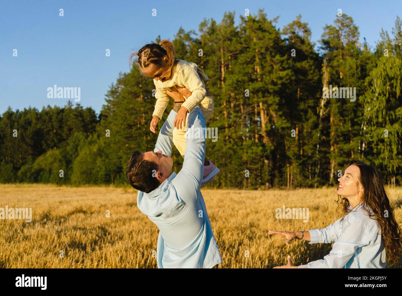 Playful parents having fun with daughter in field Stock Photo - Alamy