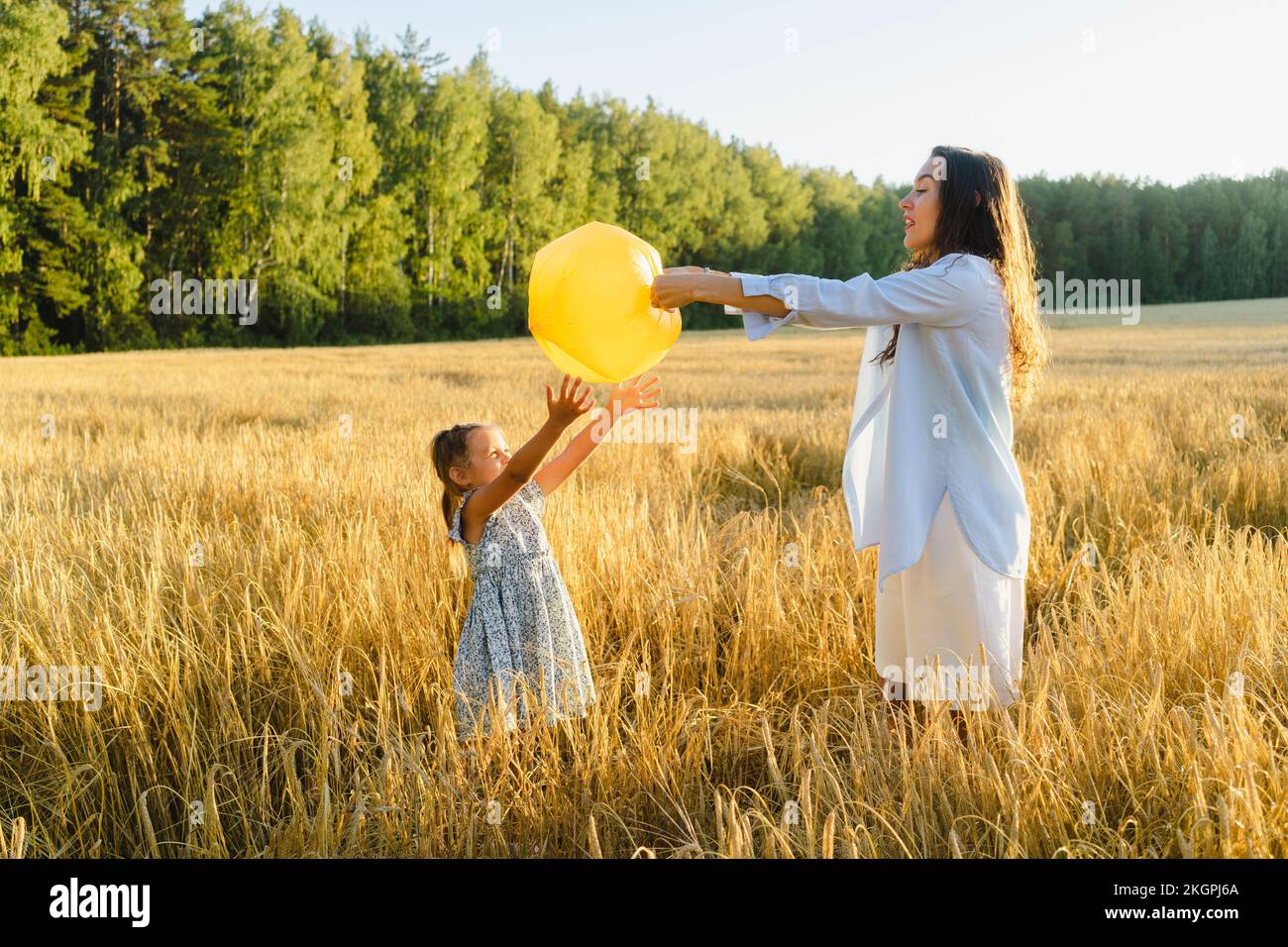 Playful daughter and mother holding garbage bag balloon in farm Stock ...