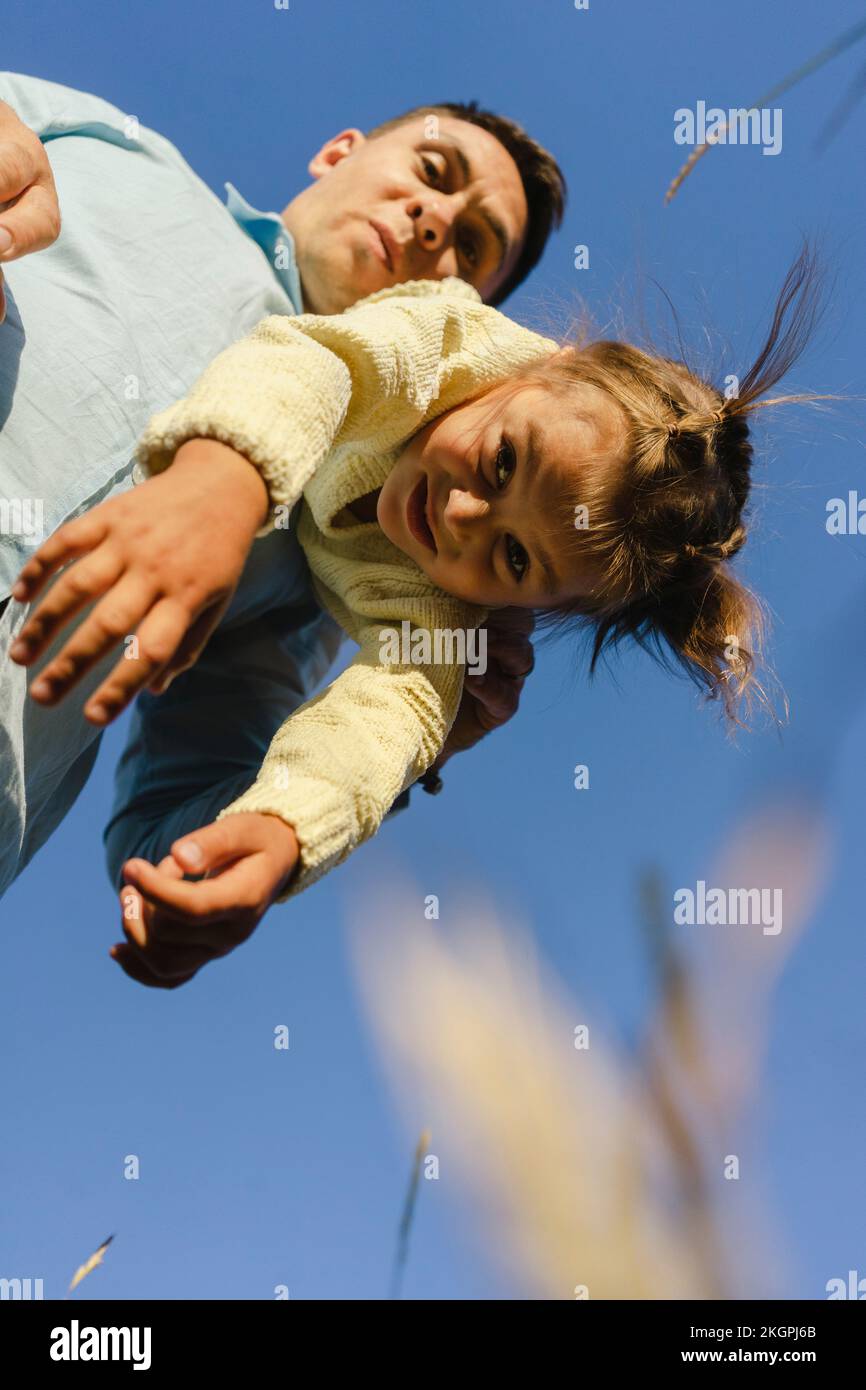 Father carrying daughter upside down under blue sky Stock Photo - Alamy