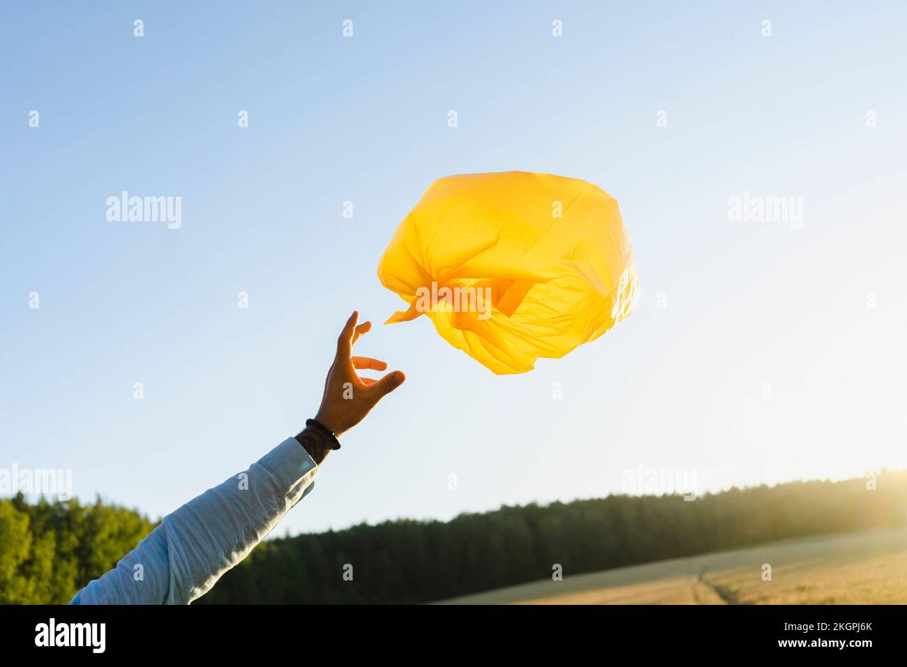 Hand of man reaching towards garbage bag balloon at field Stock Photo ...