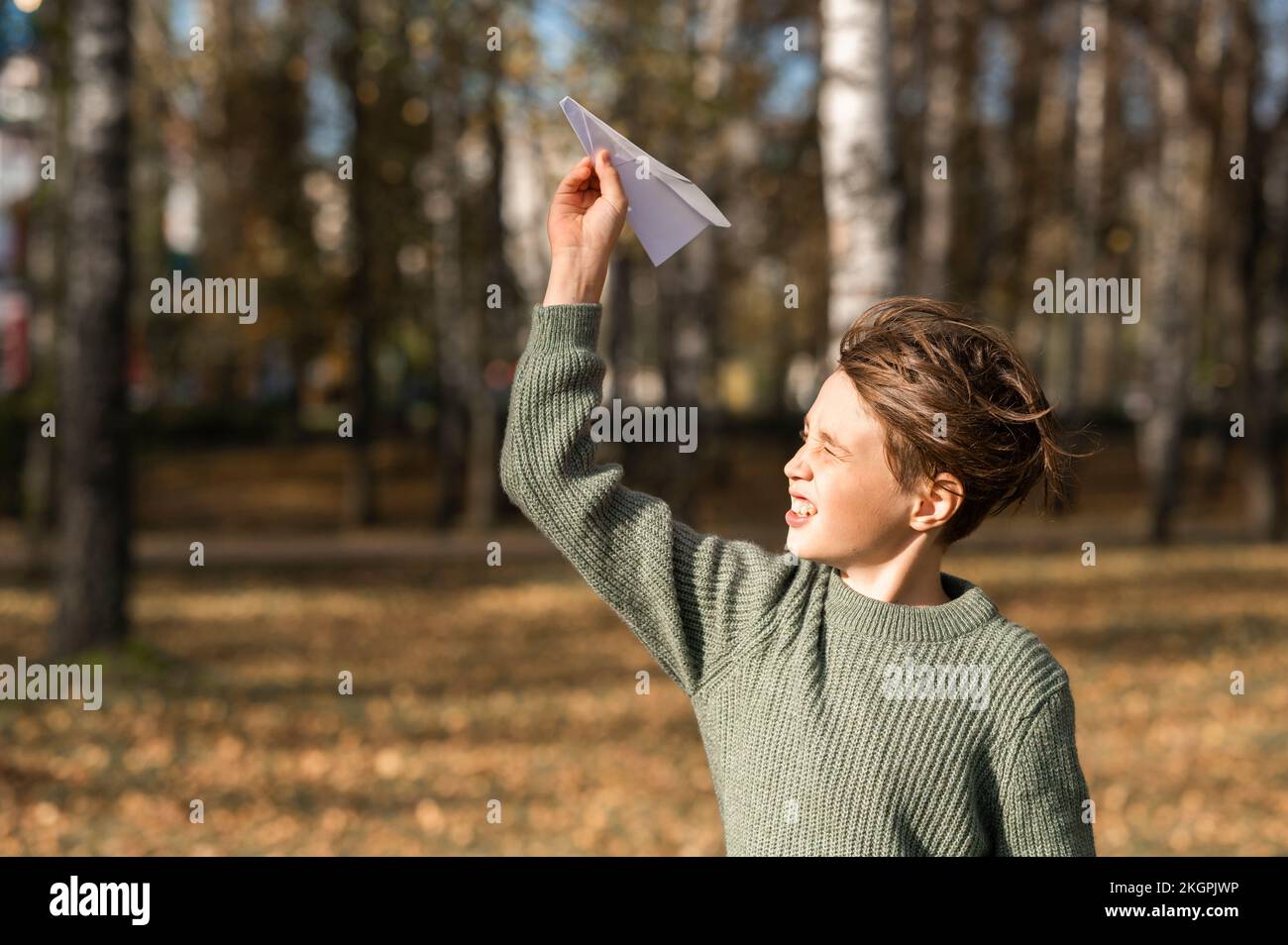 Boy playing with paper airplane in park Stock Photo - Alamy