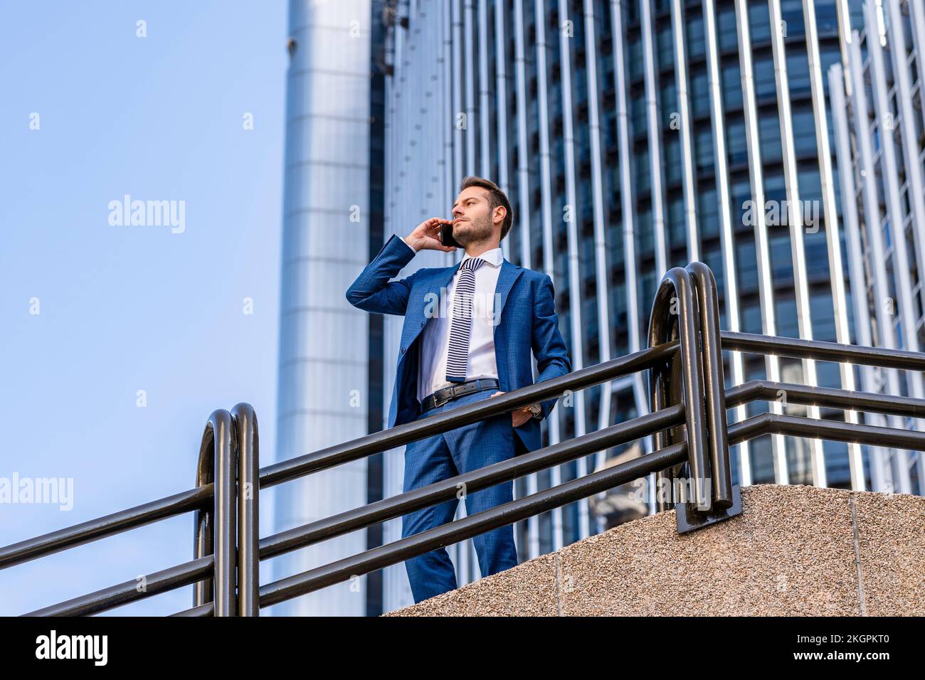 Businessman talking over mobile phone standing by railing Stock Photo ...
