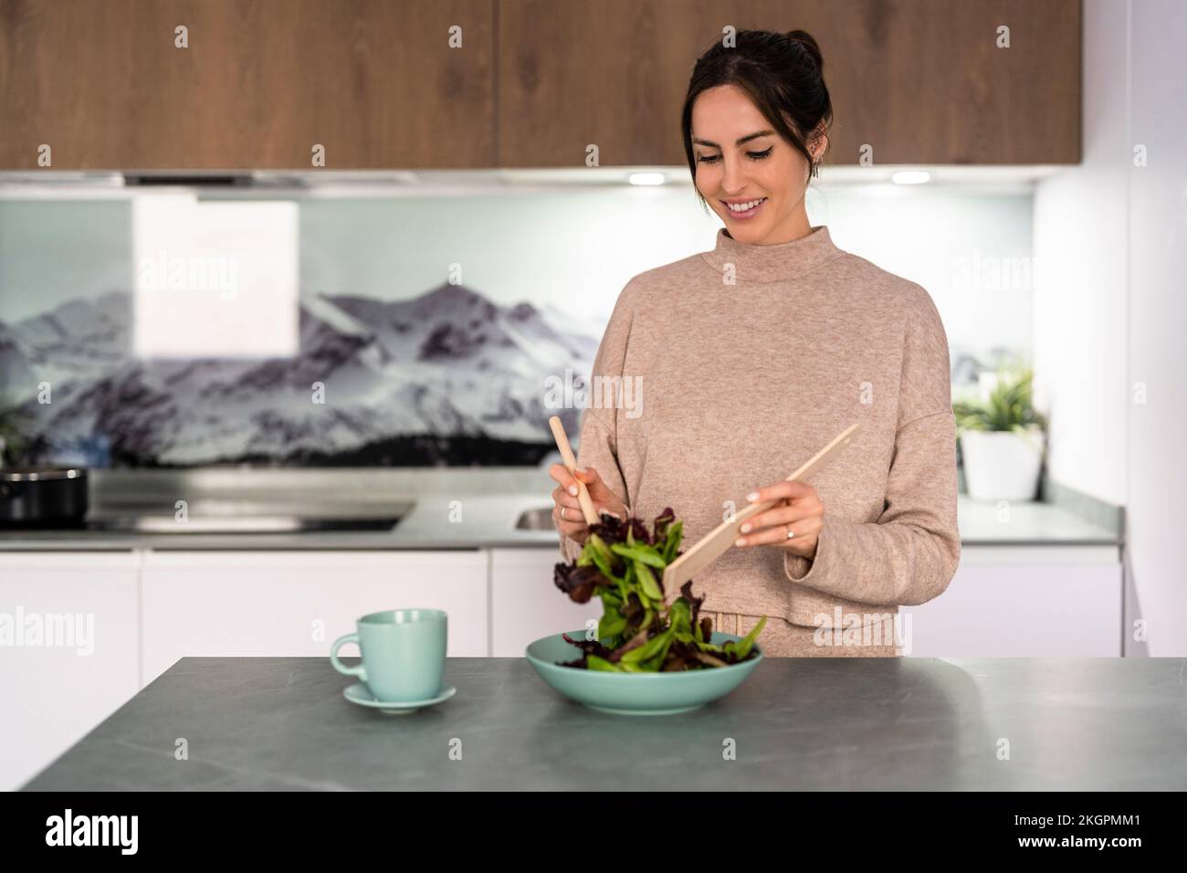 Smiling young woman preparing salad at home Stock Photo - Alamy