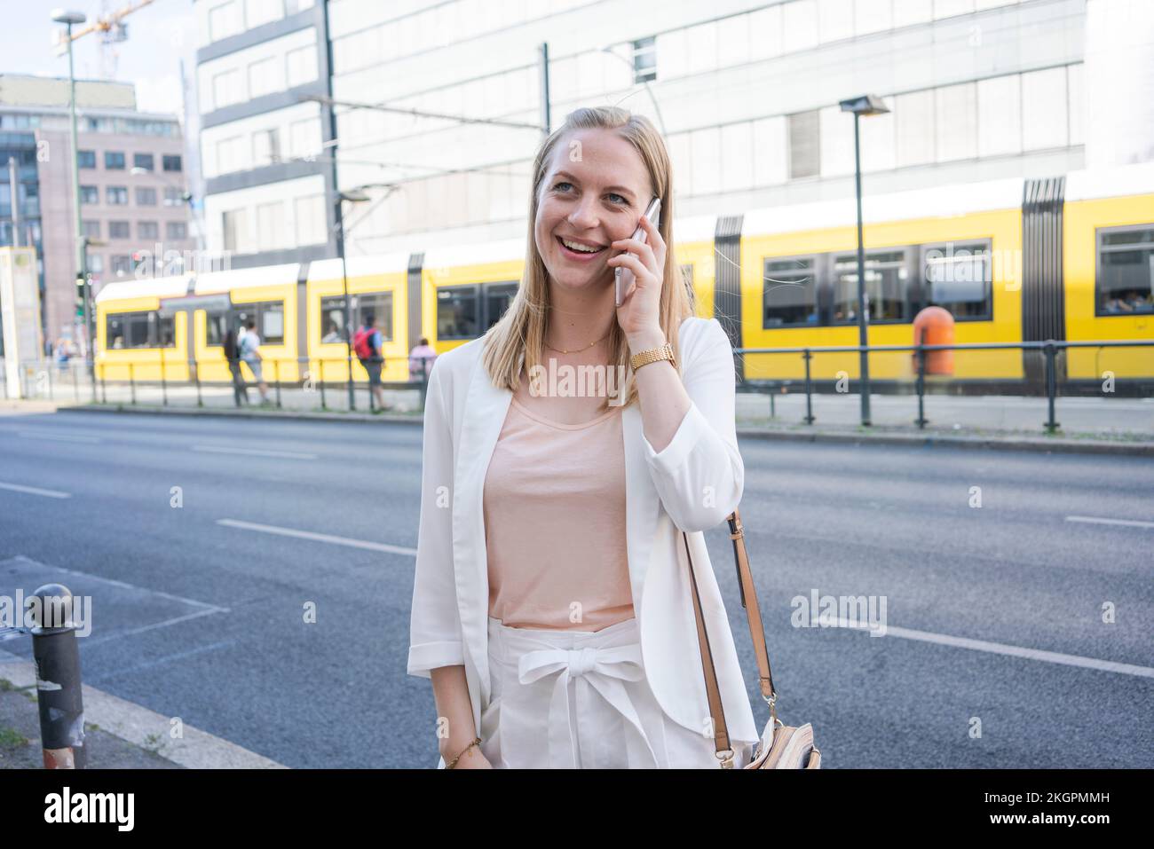 Smiling commuter talking through smart phone on road in city Stock ...