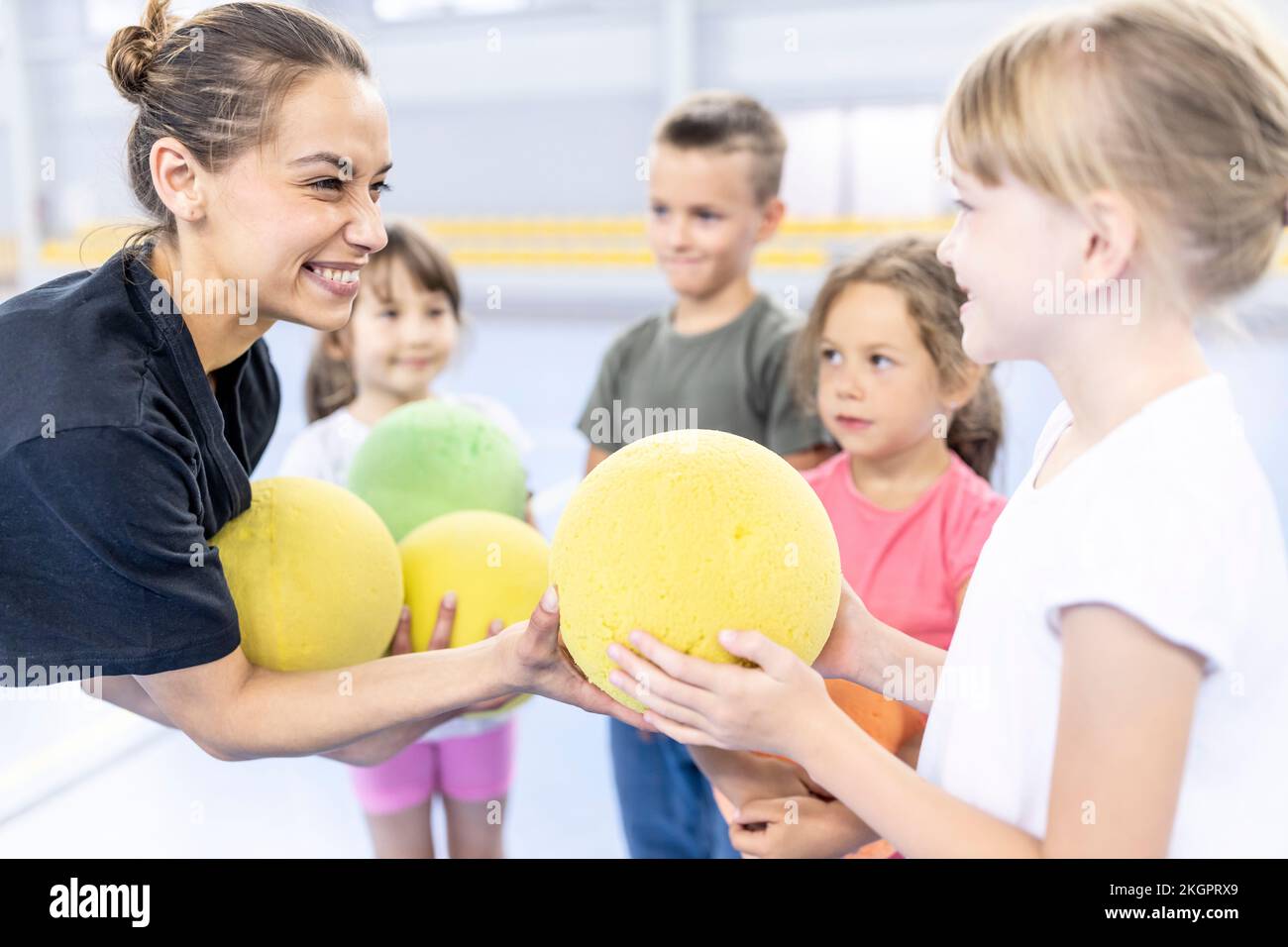 Happy teacher giving ball to student at school sports court Stock Photo ...