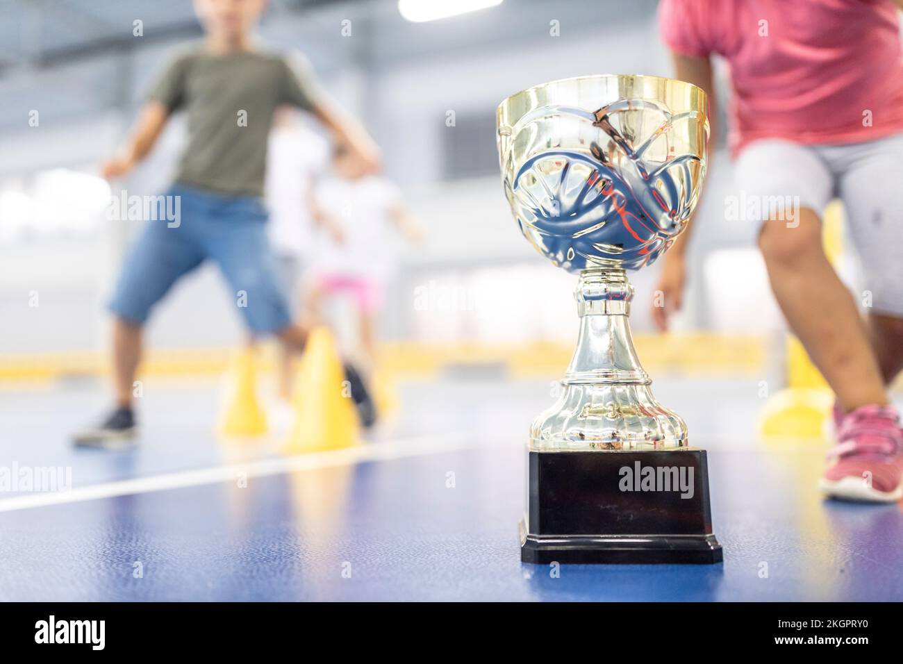 Metallic trophy cup with students in background at school sports court ...