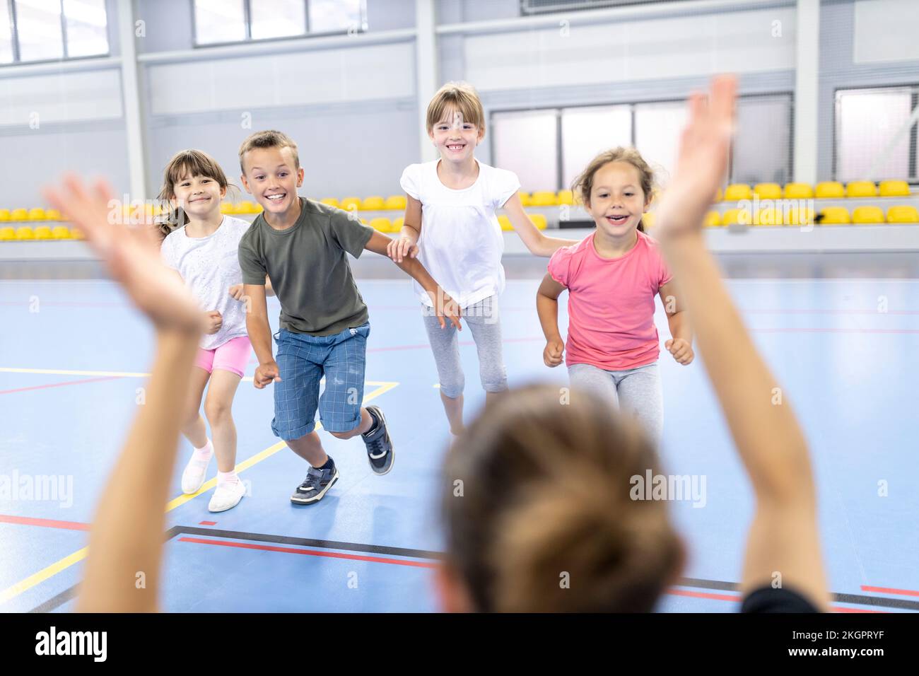 Happy students running towards teacher at school sports court Stock ...