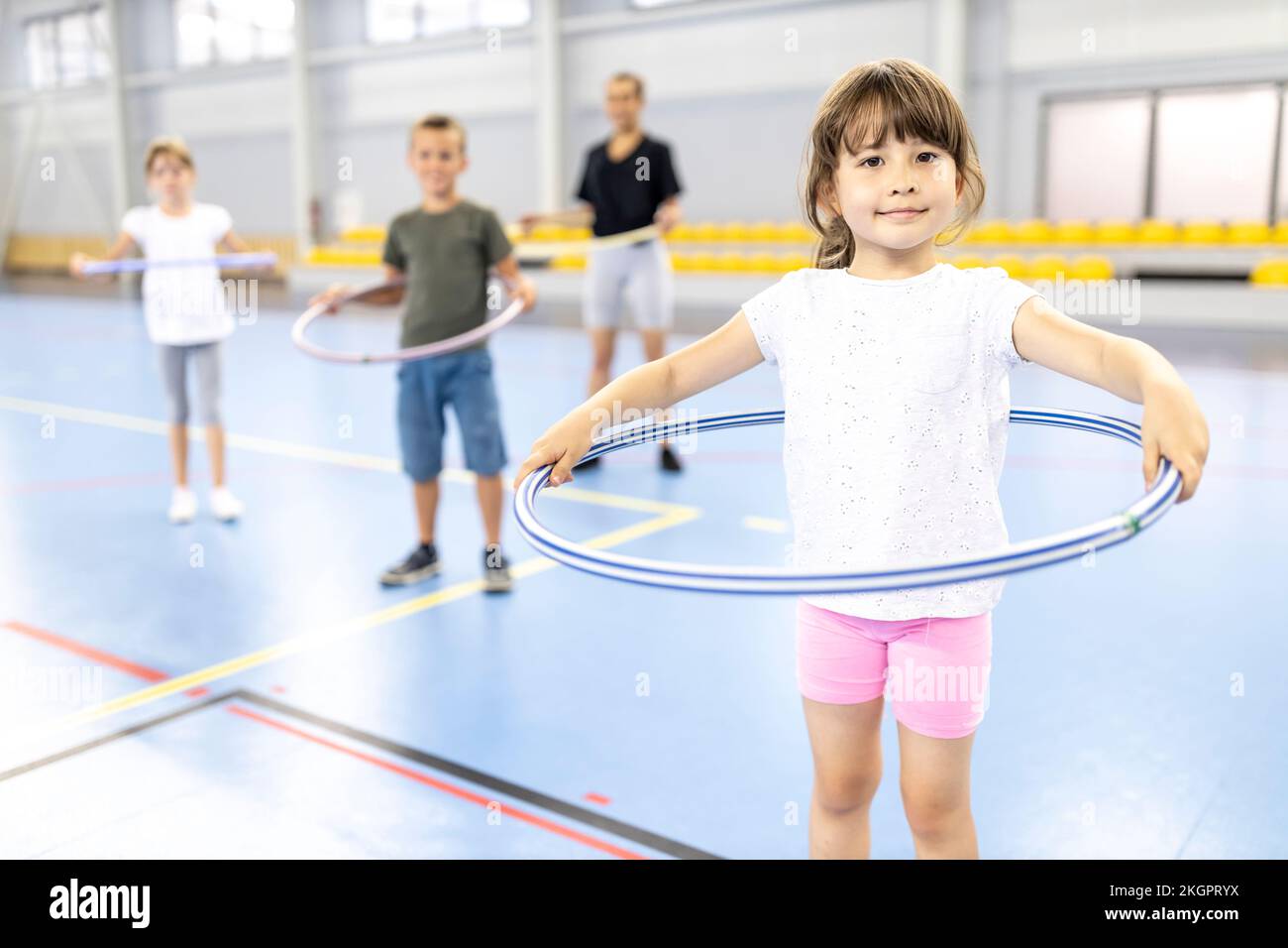 Smiling girl with hula hoop standing at school sports court Stock Photo ...