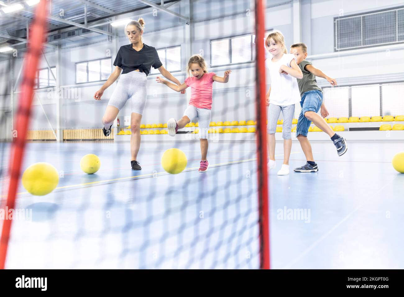 Teacher and students kicking ball in net at school sports court Stock ...