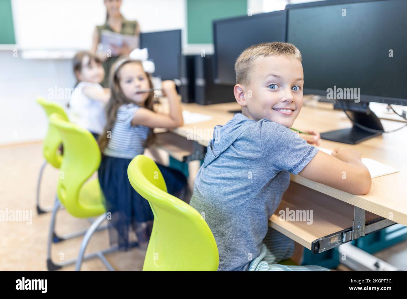 Smiling boy looking over shoulder sitting at desk in classroom Stock ...