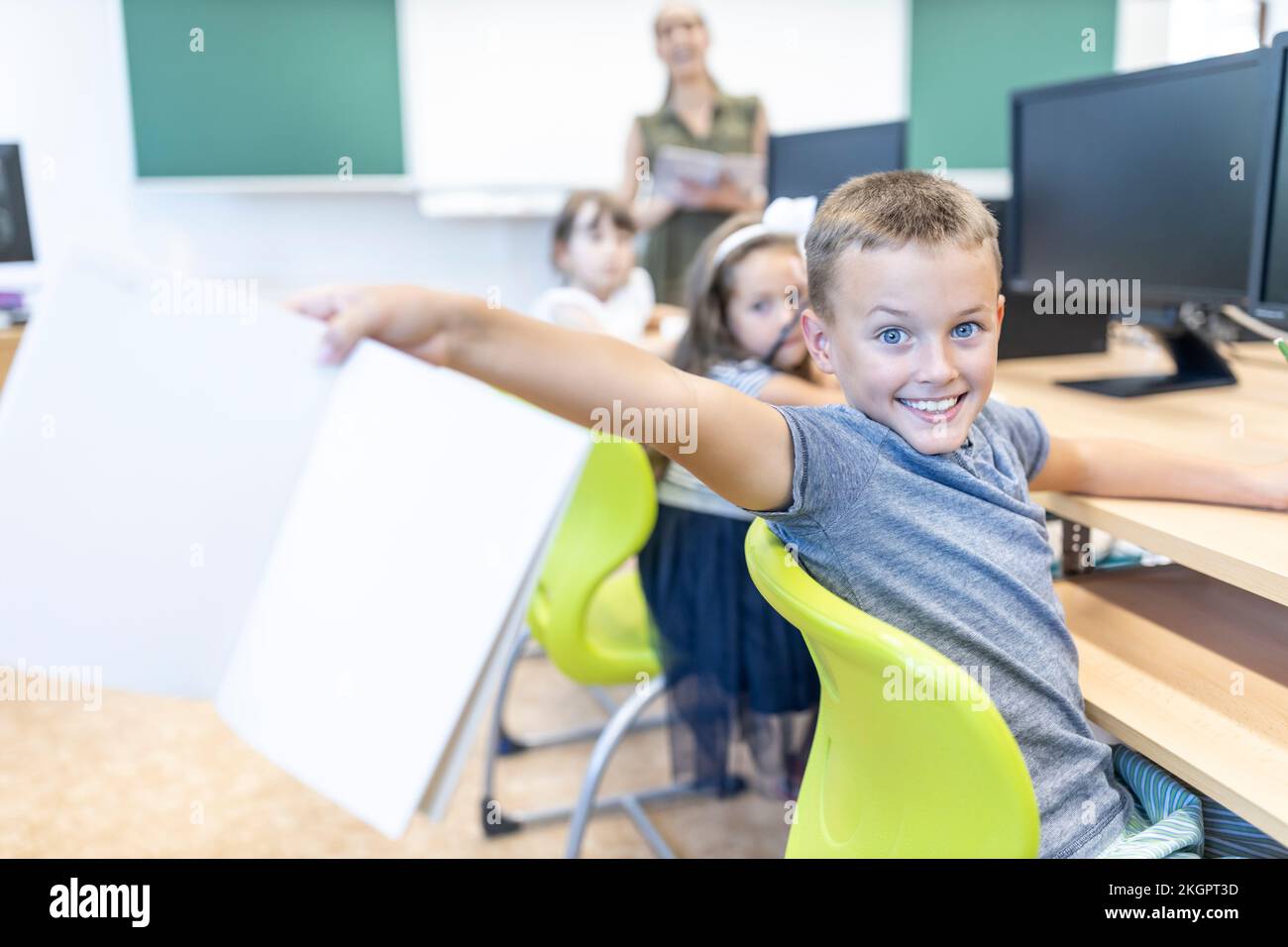 Excited boy showing notebook sitting on chair in classroom Stock Photo ...