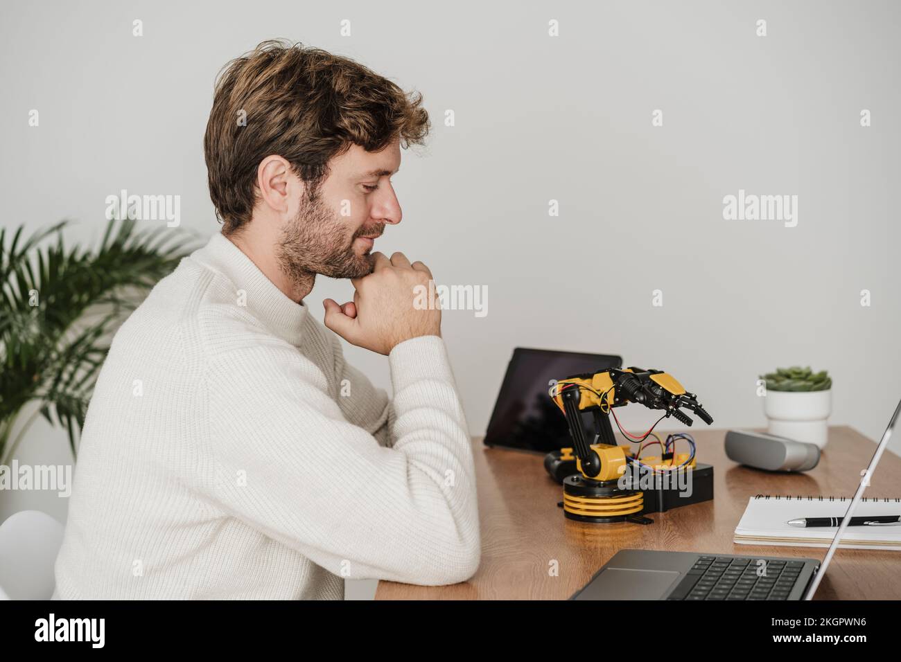 Engineer examining robotic arm on desk in office Stock Photo - Alamy