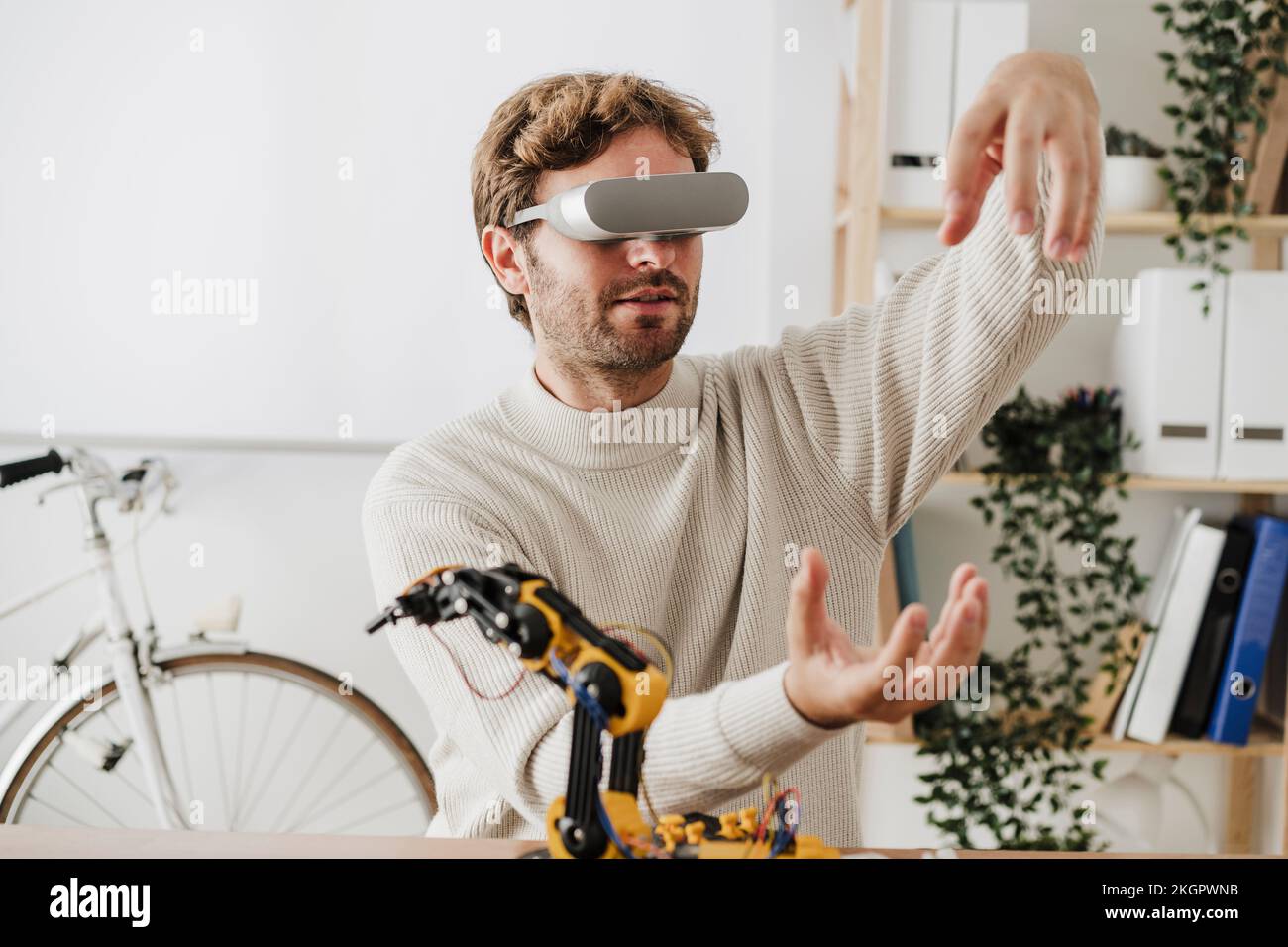 Engineer with futuristic goggles working on model of robotic arm in ...