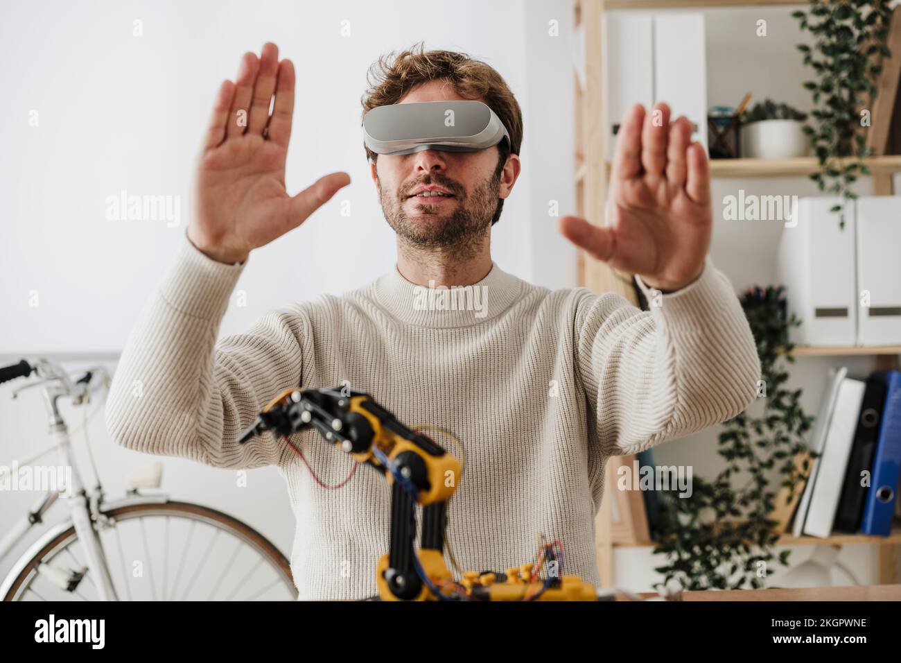 Engineer wearing VR goggles working on robotic arm in office Stock ...